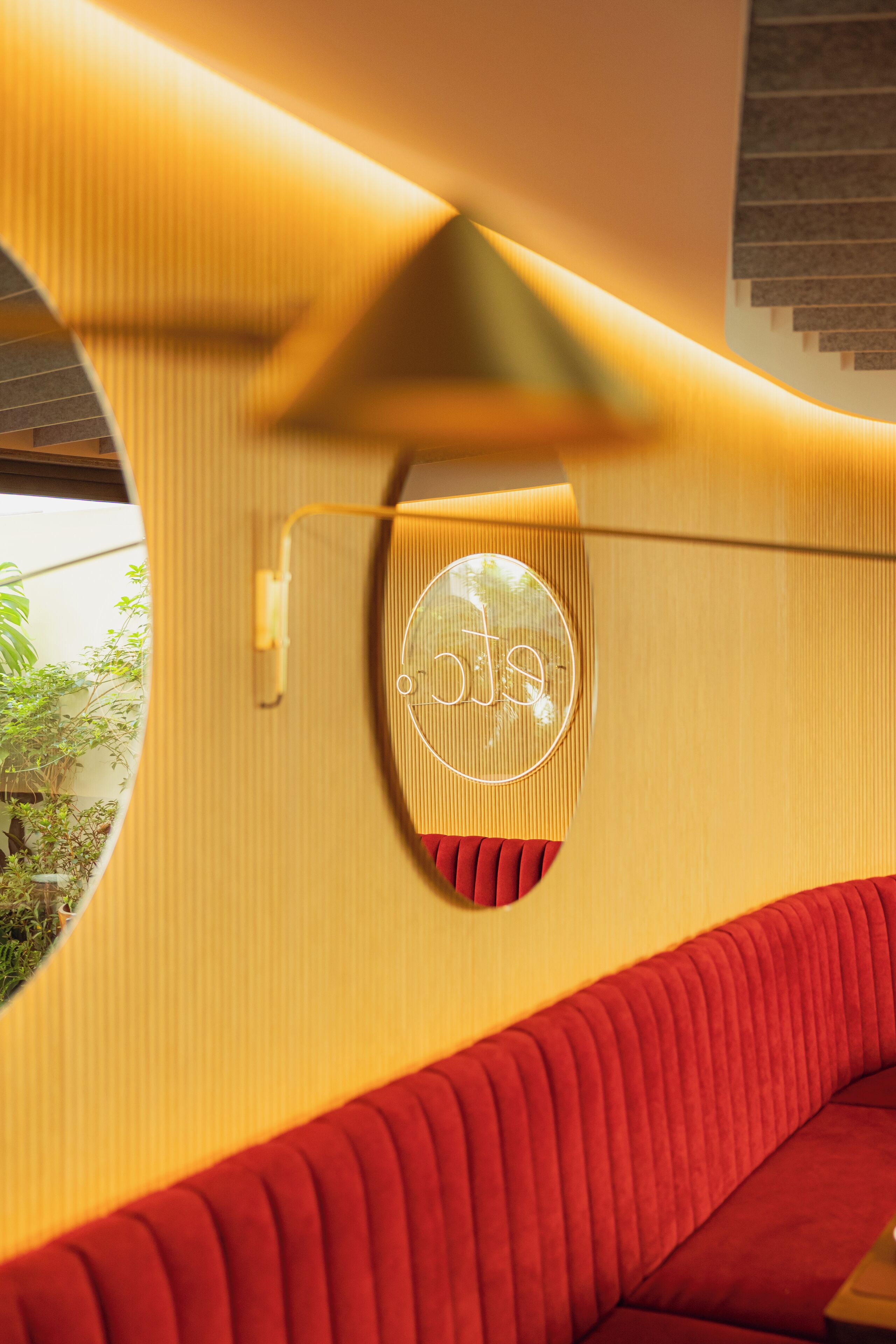 Um interior moderno com um banco estofado vermelho e uma placa circular fixada na parede.