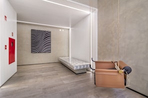Quarto moderno com balanço suspenso, um banco e parede estampada.