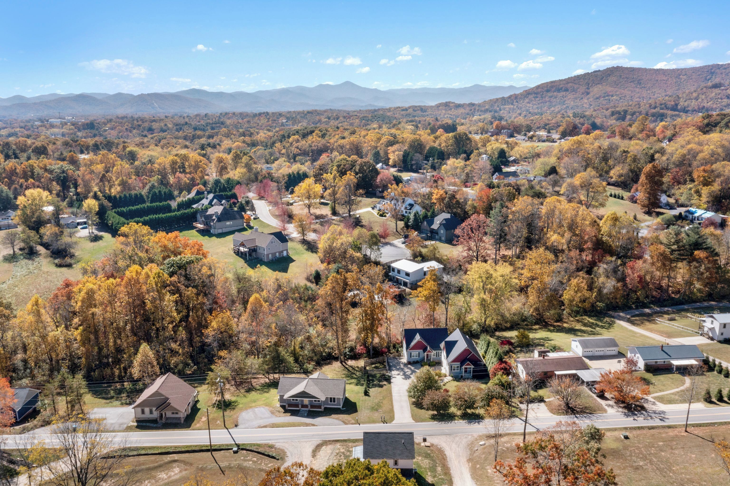 Vista aérea de um bairro residencial com casas, estradas e montanhas ao fundo.