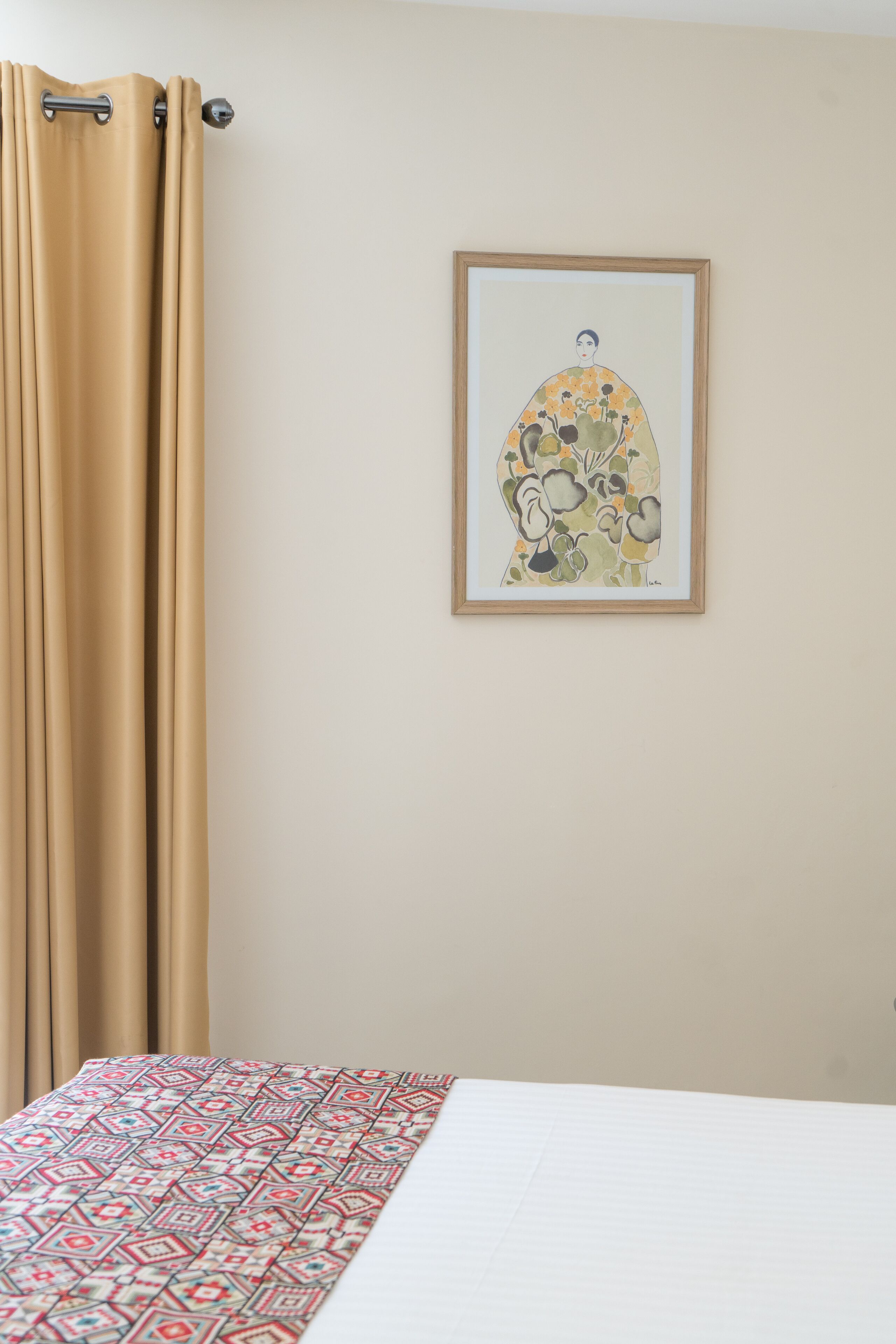 Quarto com cama, cortinas bege e um quadro na parede.