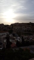 Zona residencial com edifícios, uma estrutura em cúpula numa colina e uma estrada.