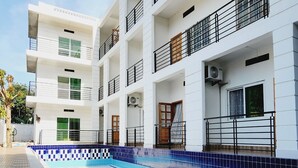 Um edifício moderno com piscina, várias varandas e céu claro.