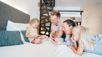 Uma família de quatro pessoas em uma cama, com uma cama beliche ao fundo.