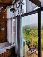 Uma cabana de madeira com varanda envidraçada, um deck de madeira e uma banheira.