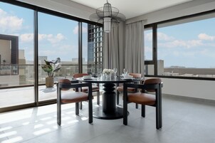 Uma área de jantar moderna com uma mesa redonda, cadeiras e um candelabro.