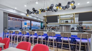 Uma área de bar moderna com balcão, banquetas e espaço de estar com mesas e cadeiras.