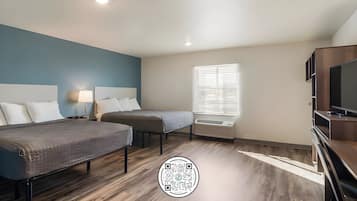 Quarto de hotel com duas camas, uma televisão e uma janela com persianas.
