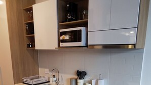 Uma cozinha moderna com armários brancos, micro-ondas embutido e máquina de lavar louça.