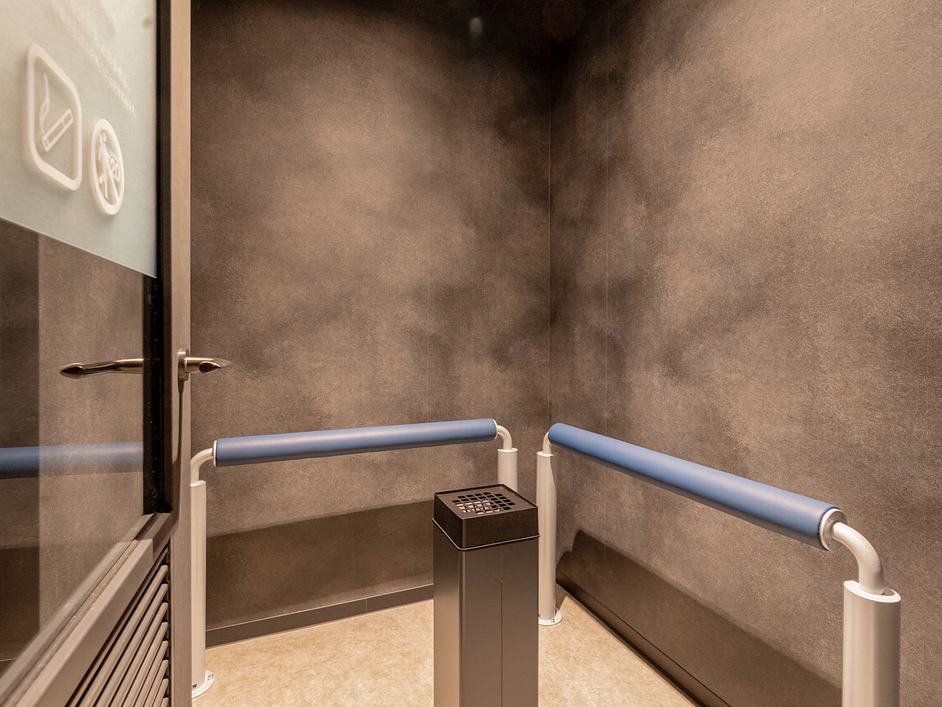 Um elevador moderno com acabamento metálico, portas de vidro e painel de controle.