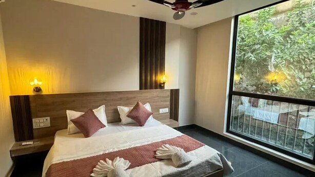Quarto de hotel com uma cama grande, um ventilador de teto e uma varanda com vista para o verde.