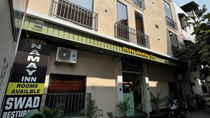 Um hotel com uma placa indicando 'Hotel Nam May Inn' e 'Quartos Disponíveis'.