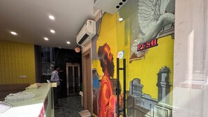 Uma área de recepção de hotel com piso de mármore, balcão de atendimento e um grande mural na parede.