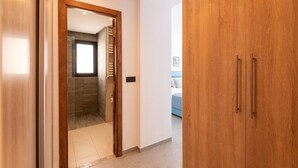 Um corredor com um guarda-roupa de madeira e uma porta que dá para um quarto com cama e janela.