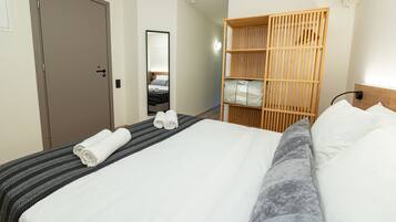 Quarto de hotel com cama, guarda-roupa, espelho e ar condicionado.