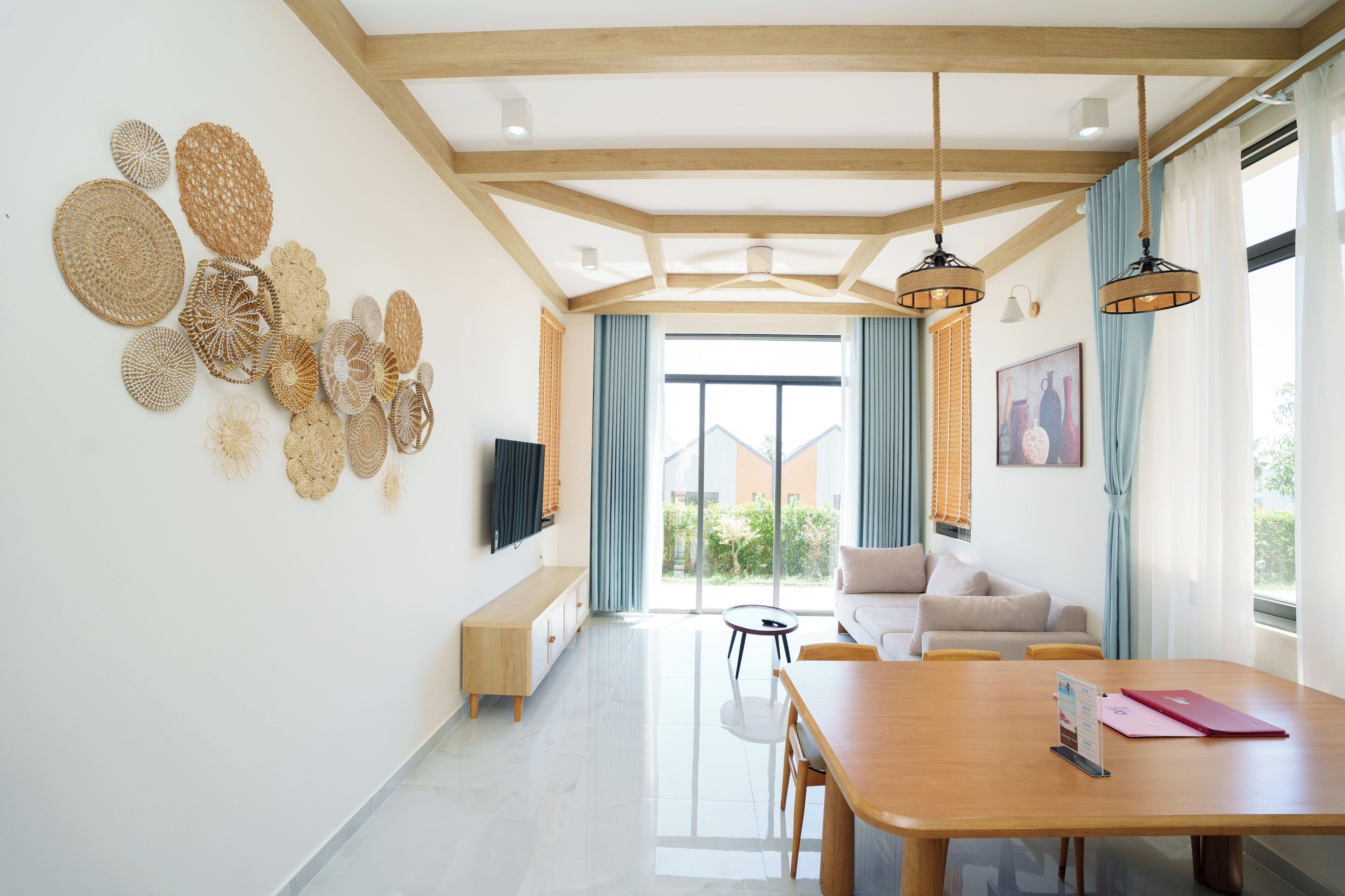 Uma sala de estar moderna com uma mesa de jantar de madeira, um sofá e uma televisão fixada na parede.
