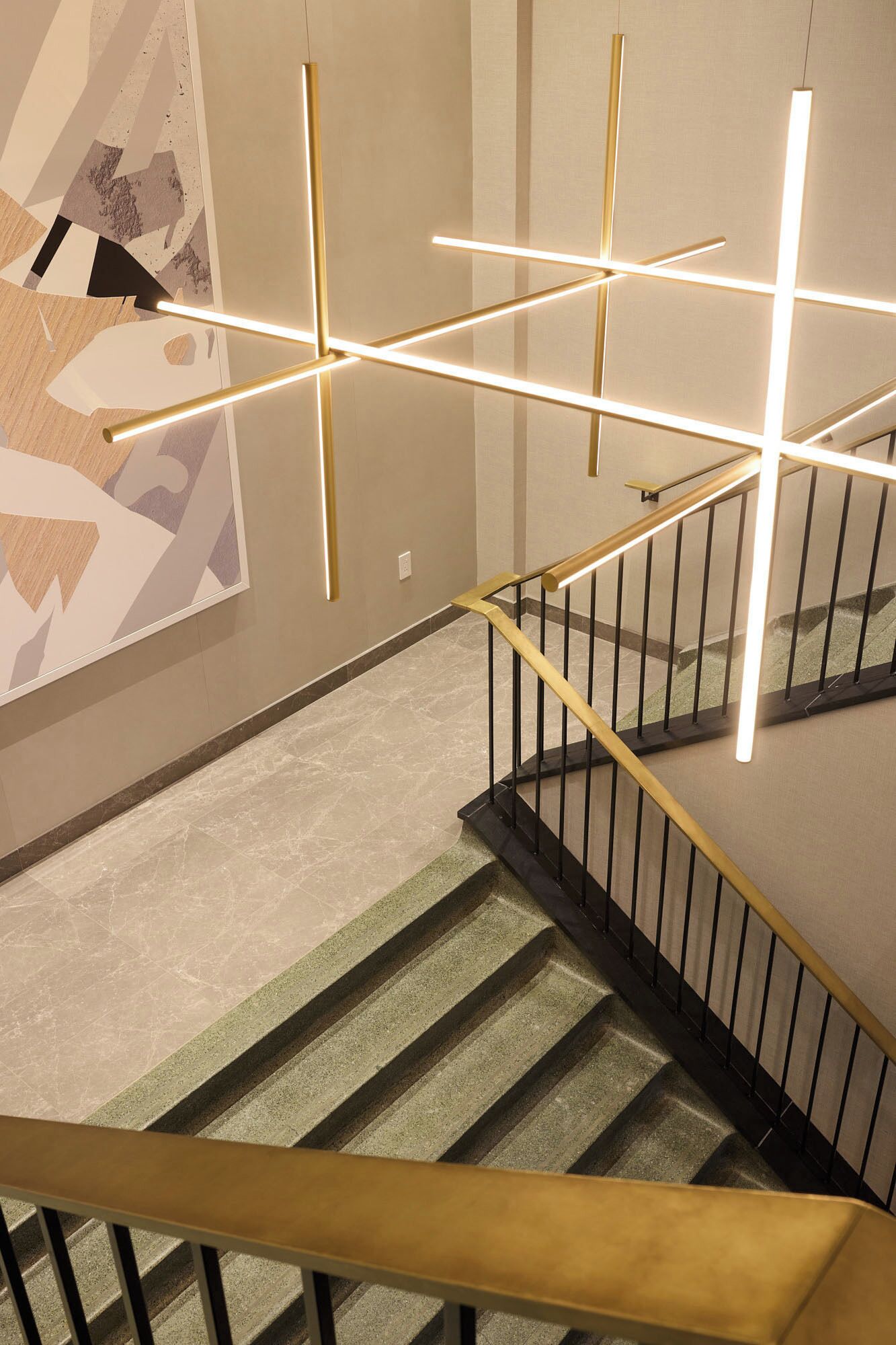 Uma escadaria com corrimão, uma parede com arte abstrata e uma luminária moderna.