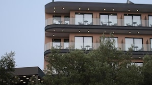 Hotel com vários andares, varandas, janelas amplas e áreas de estar ao ar livre.