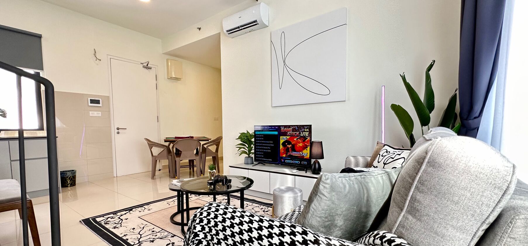Uma sala de estar moderna com um sofá, uma mesa de centro e uma televisão. Há uma área de jantar com cadeiras e uma mesa.