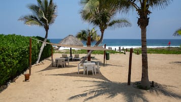 Na praia, areia branca, espreguiçadeiras, guarda-sóis