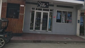 Um edifício de dois andares com uma placa indicando 'HOSPEDAJE' e uma placa de 'Sugar Shop'.