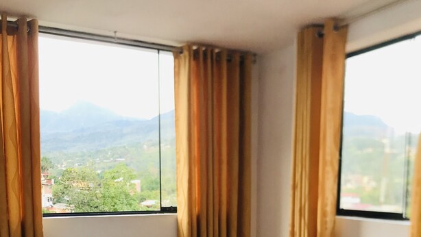 Quarto de hotel com cama, cortinas e vista para montanhas.