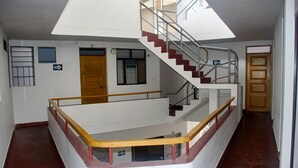 Interior em vários níveis, com escada, patamar e uma porta com a inscrição 'SALIDA'.