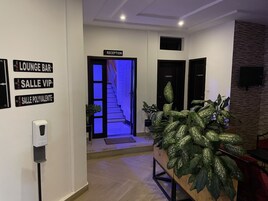 Uma área de recepção de hotel com placas indicando lounge bar, salle vip e salle polivalente.