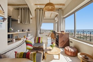 Uma sala de estar acolhedora com um sofá, uma mesa de centro e vista para o mar.