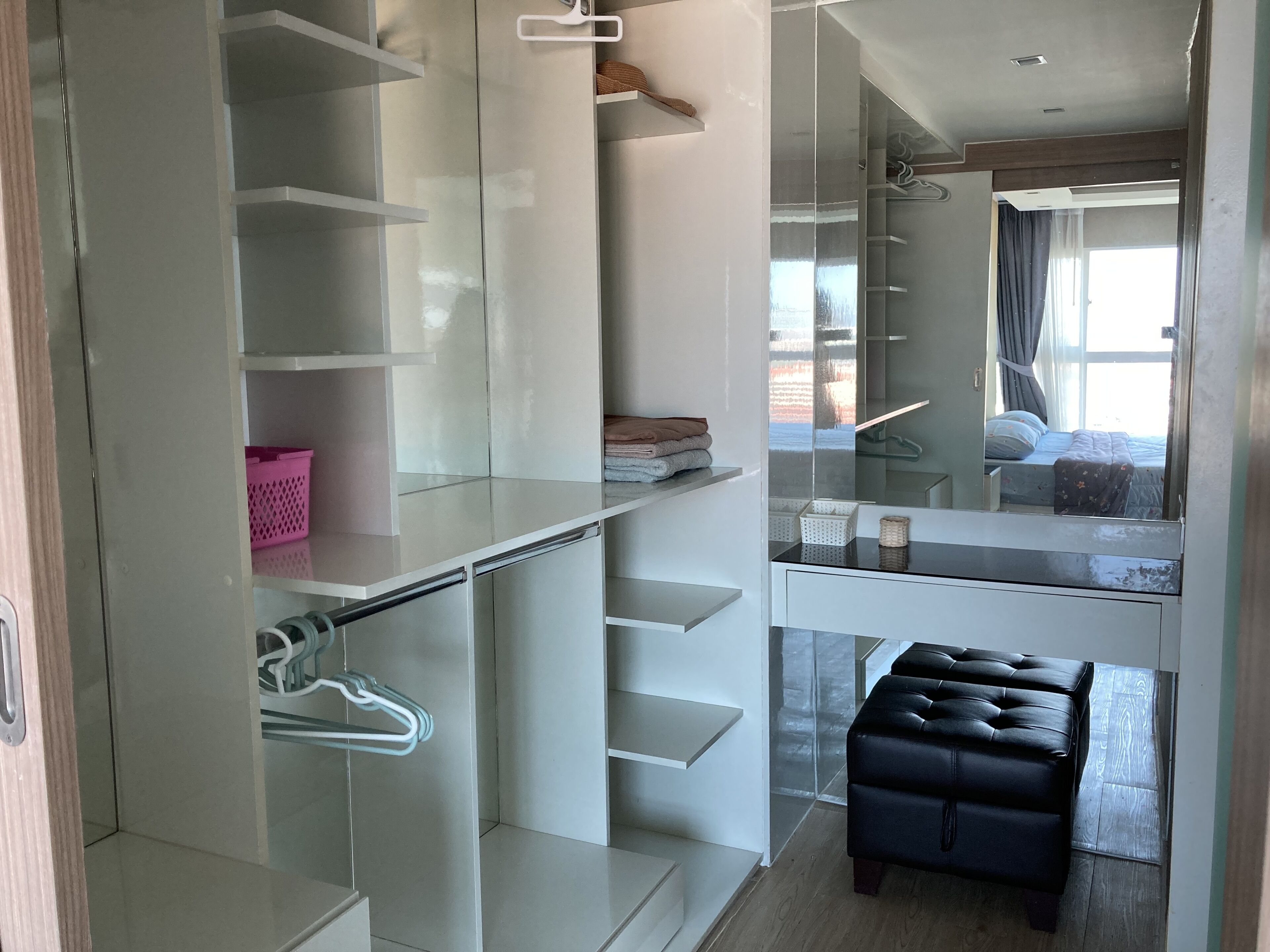 Um closet moderno com prateleiras abertas, um banco e um espelho.