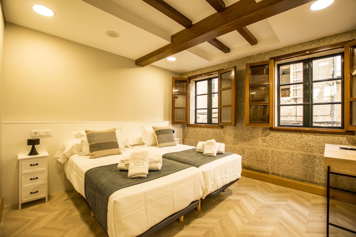 Quarto de hotel com uma cama grande, uma escrivaninha e uma janela com vários painéis.