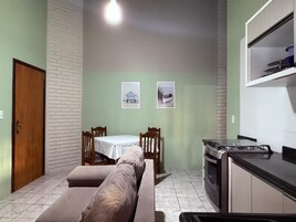 Um espaço compacto com cozinha compacta, área de refeições com mesa e cadeiras, e um sofá.