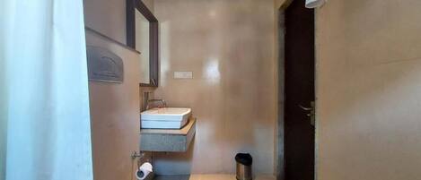 Uma casa de banho pequena e compacta com uma sanita, um lavatório e um espelho.