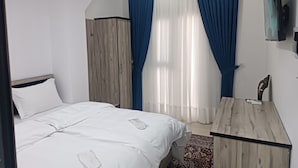 Quarto com cama, guarda-roupa de madeira, escrivaninha e espelho.