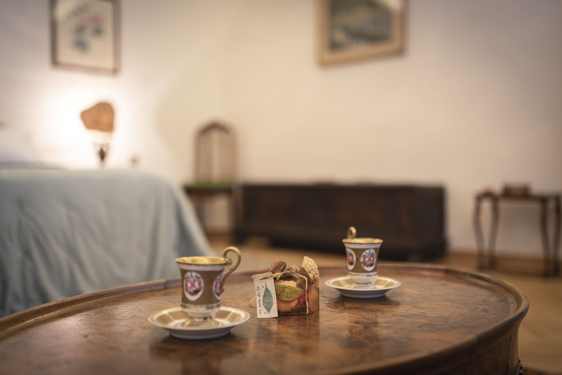 Uma mesa de madeira redonda com duas chávenas elaboradas e uma pequena caixa decorativa.