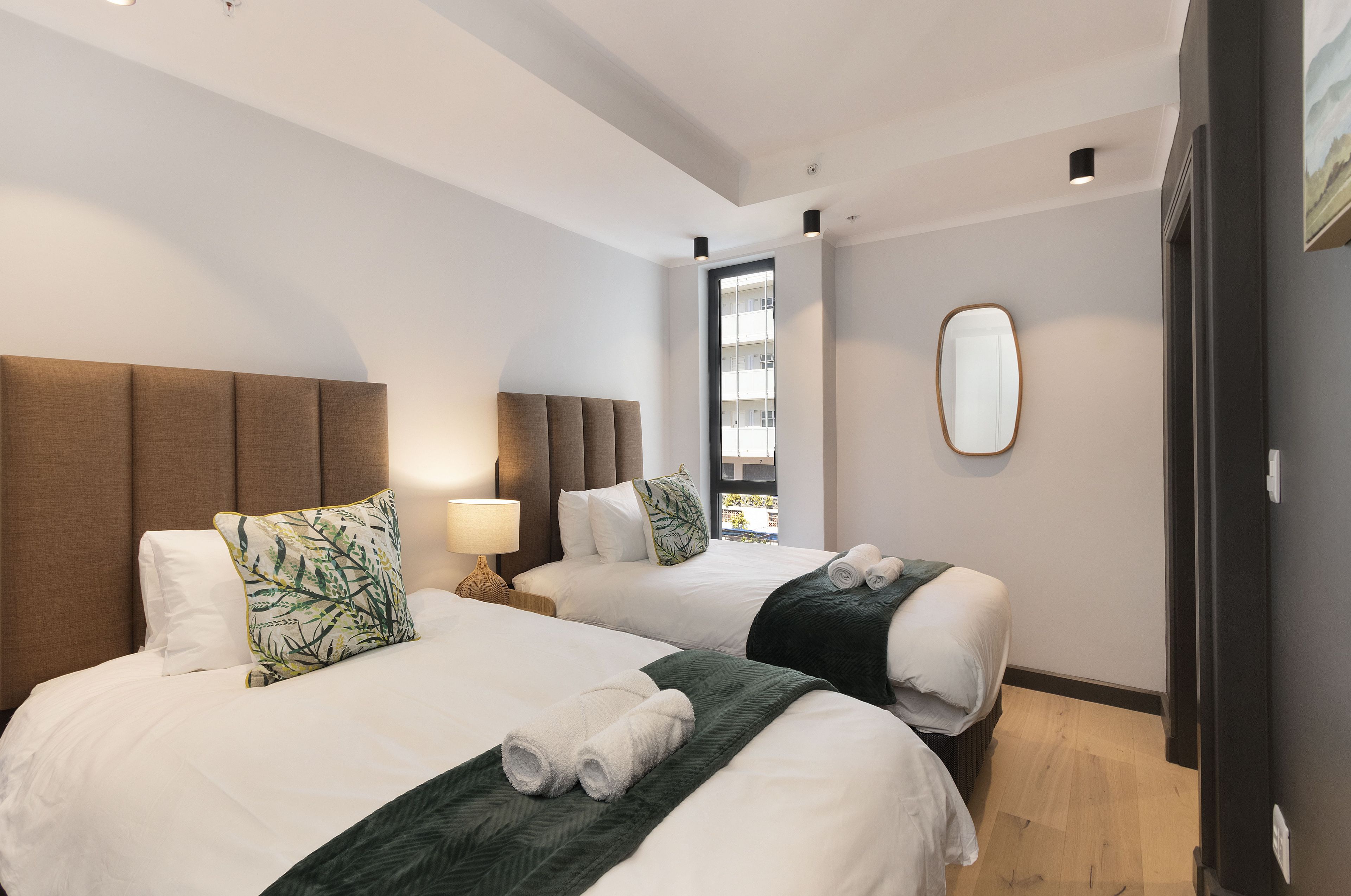 Quarto de hotel com duas camas, um espelho grande e vista para o exterior.