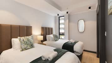 Quarto de hotel com duas camas, um espelho grande e vista para o exterior.