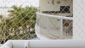 Um hotel com vários andares, varandas, piscina e vista para palmeiras e montanhas.