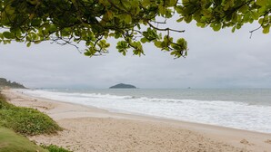 Uma praia com areal, ondas e uma ilha ao longe.
