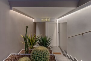 Um corredor moderno com escada, paredes brancas e uma placa com a inscrição "TAORMINA ES TOWN".