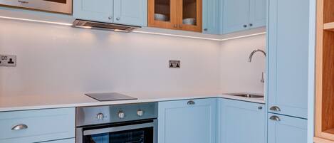 Uma cozinha com armários azul-claros, forno embutido e micro-ondas.