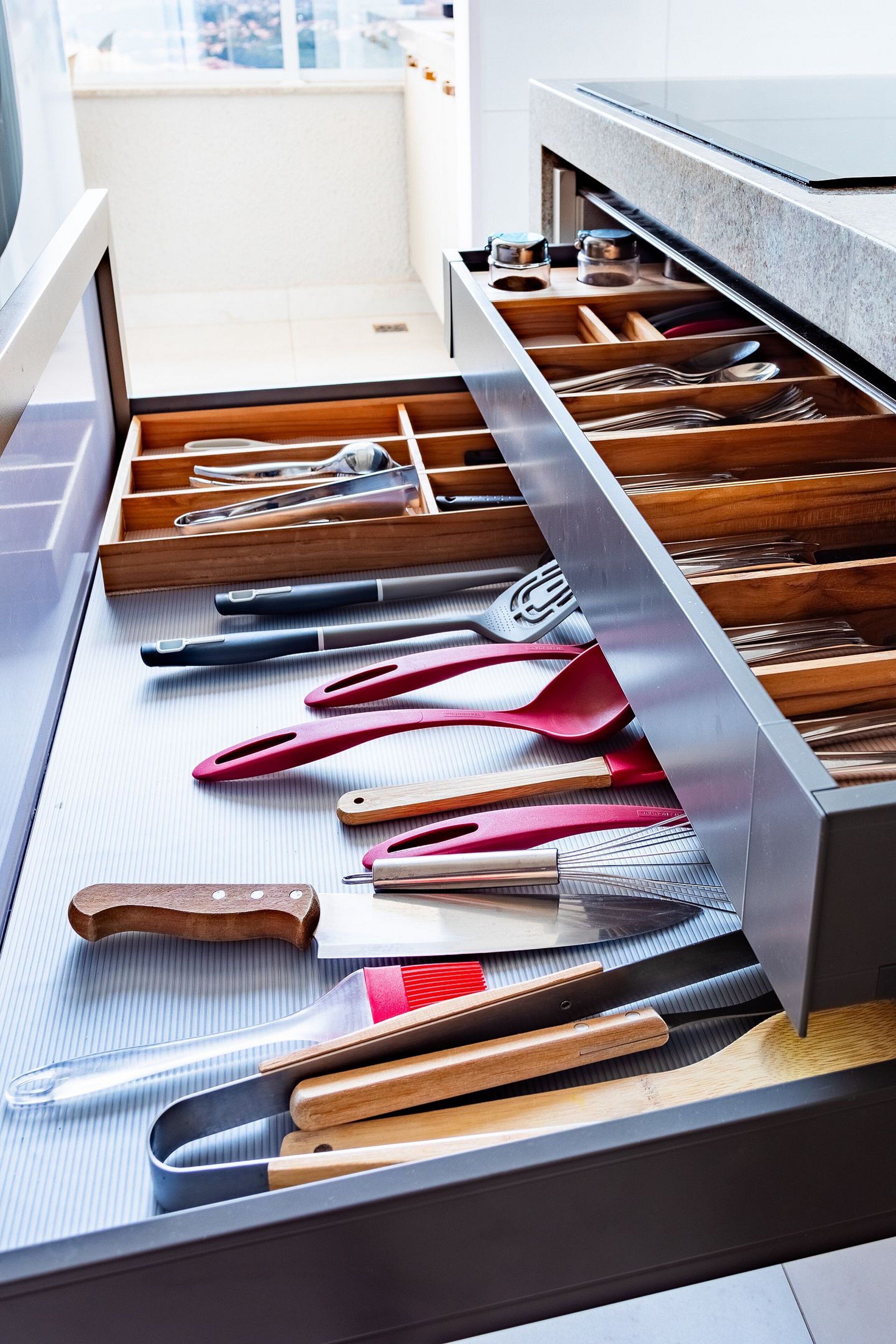 Uma gaveta de cozinha com utensílios e panelas.