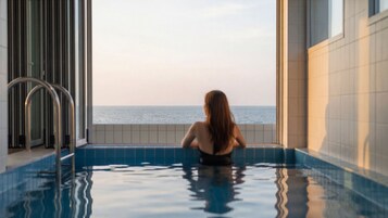 Uma pessoa em uma piscina com vista para o mar.