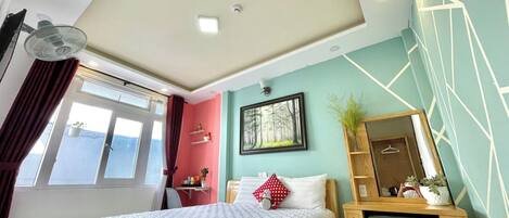Quarto com cama, escrivaninha, cadeira, janela e ventilador de teto.