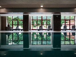 Área da piscina com espreguiçadeiras e amplas janelas com vista para o verde.