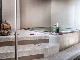Uma área de spa com hidromassagem, escadas revestidas e abóboras decorativas.