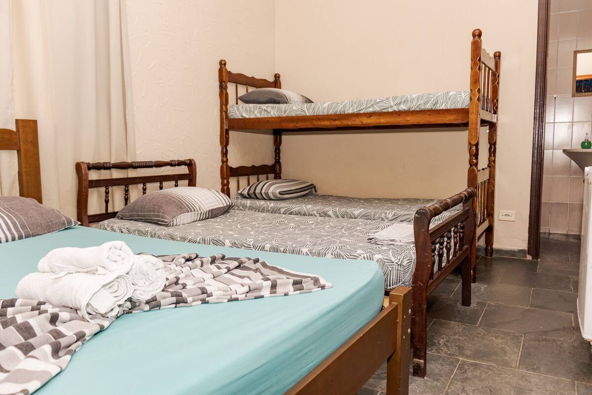 Quarto com beliche, colchão azul, cabeceira de madeira e uma pequena mesa de cabeceira com espelho.