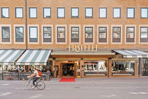 A building with a sign reading "FRATELLI" and a red carpet leading to the entrance.