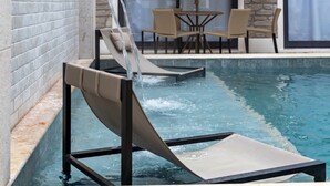 Piscina interna com escorrega, mesa com cadeiras e um grande guarda-sol.