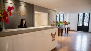 Uma receção com design moderno, uma rececionista e plantas decorativas.