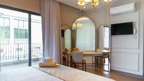 Quarto de hotel com uma cama grande, uma mesa com cadeira, um espelho, televisão e varanda com vista para o exterior.